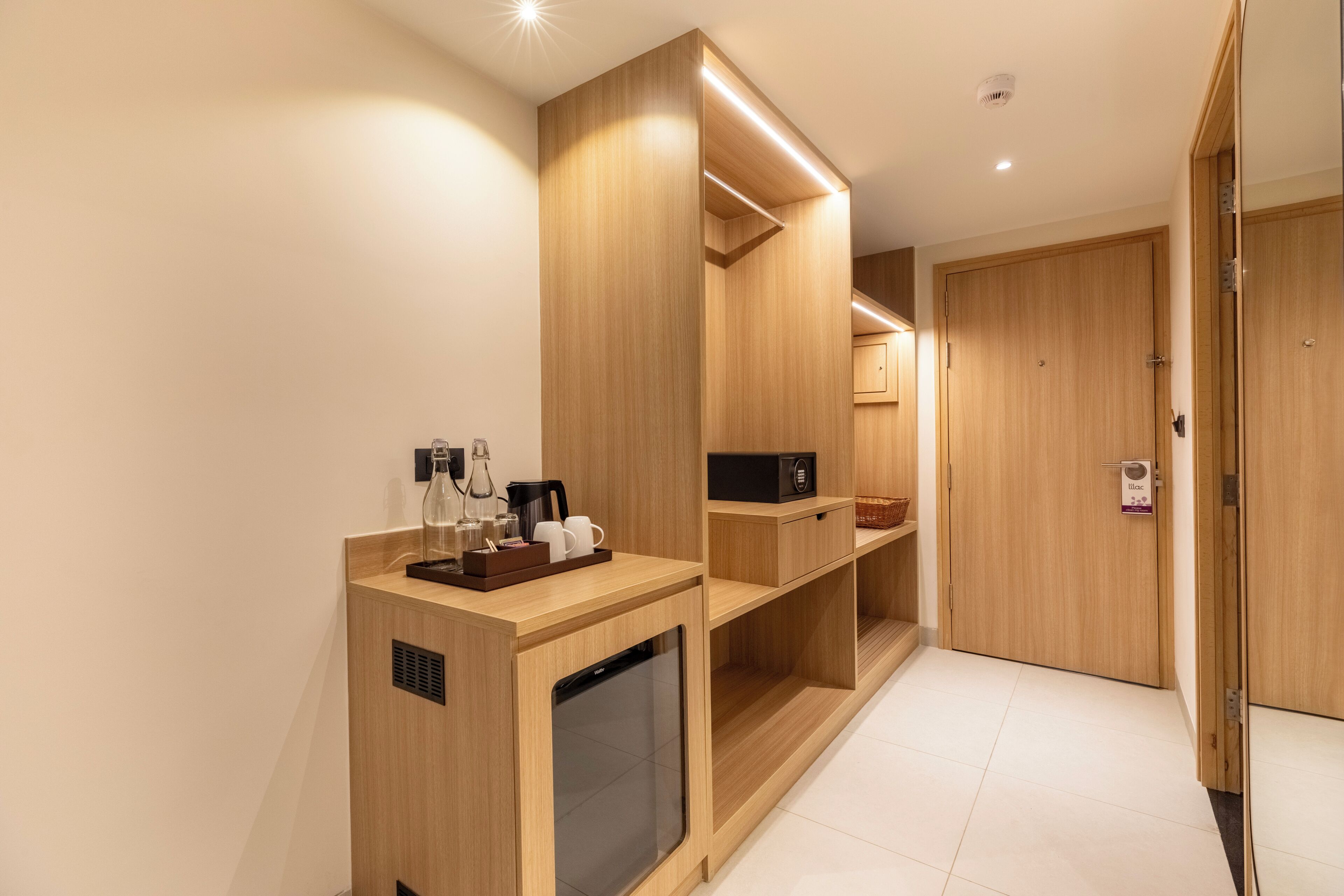 Quarto de hotel moderno com toucador de madeira, micro-ondas e mini-frigorífico.