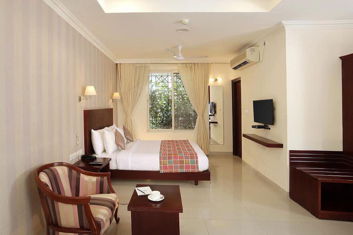Quarto de hotel com cama, televisão, escrivaninha e cadeira.