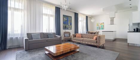 Uma sala de estar moderna com carpete cinza, dois sofás, uma mesa de centro de madeira e um lustre.
