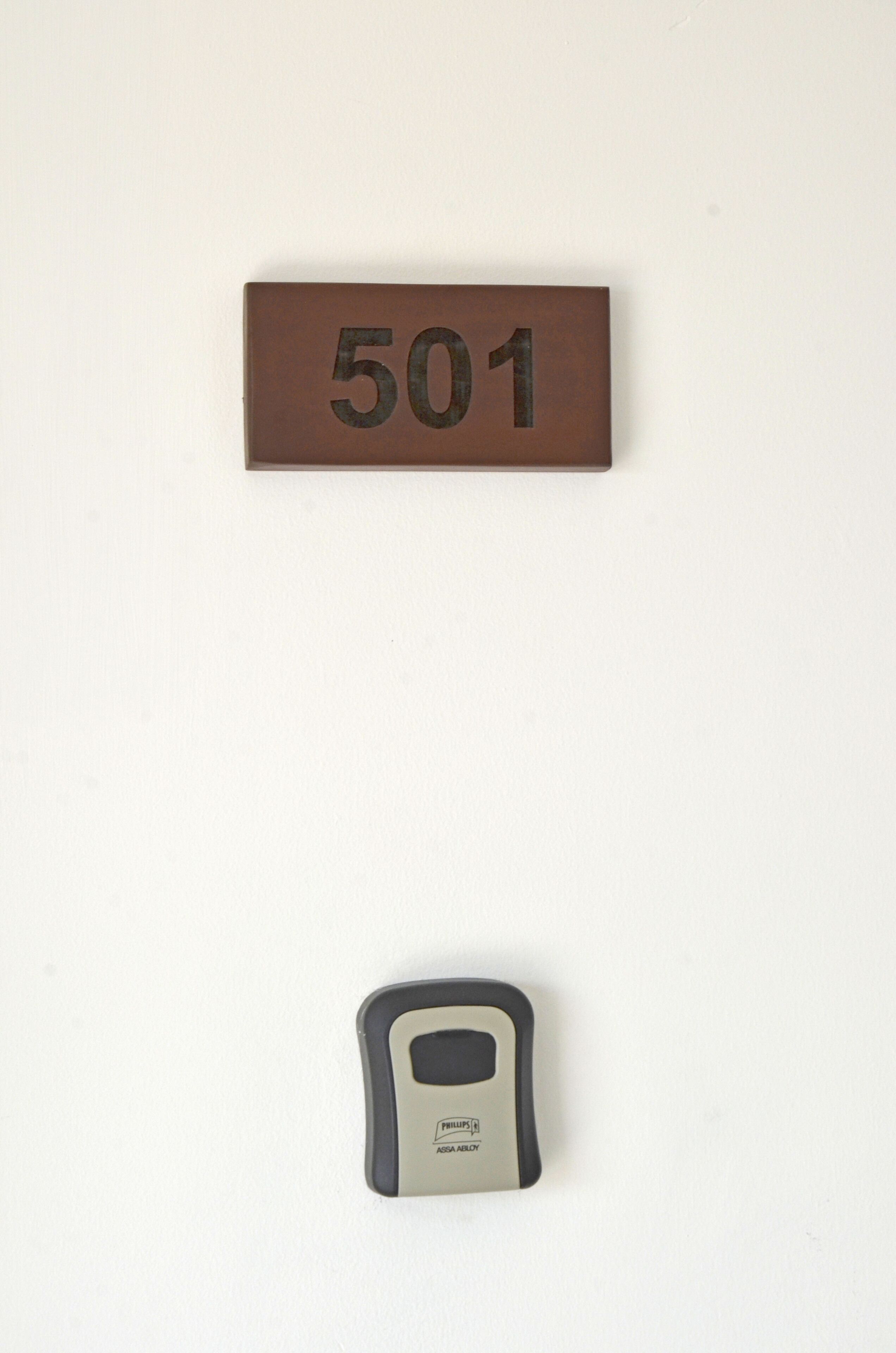 Placa marrom com o número 501 e um dispositivo preto e bege abaixo.