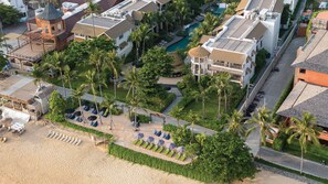 Vista aérea de um resort com piscina, área de praia e vários edifícios.