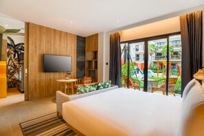 Quarto de hotel com uma cama grande, televisão, mesa pequena e varanda com mobiliário de exterior.