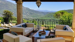 Terraço com área de estar ao ar livre e vista para uma paisagem montanhosa.