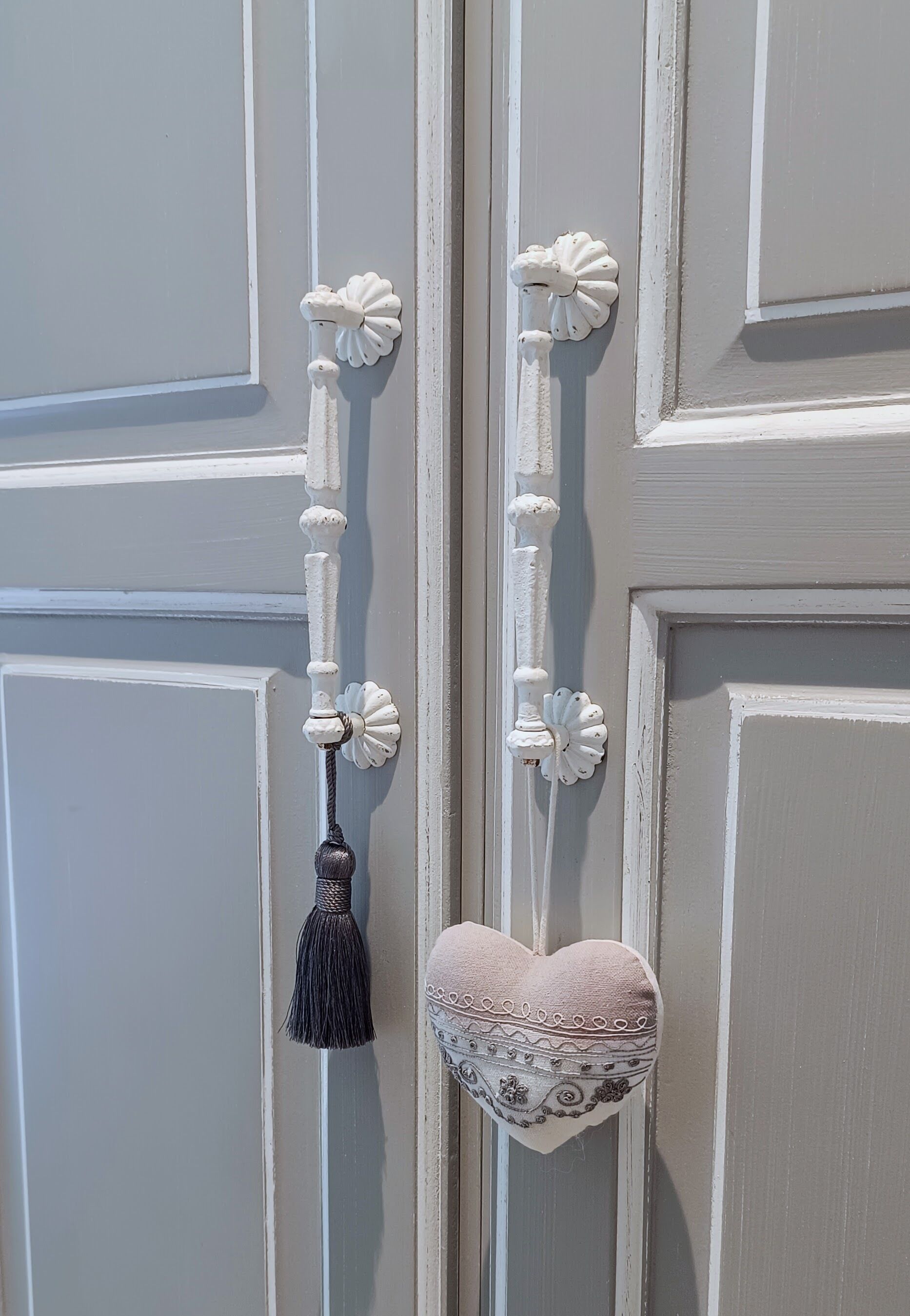 Uma porta com maçaneta decorativa branca e um ornamento em formato de coração.