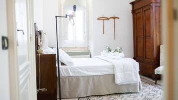 Um quarto com cama, guarda-roupa de madeira, luminária pendente e piso estampado.