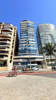 Uma rua urbana moderna com edifícios altos, área pavimentada e alguns pedestres.