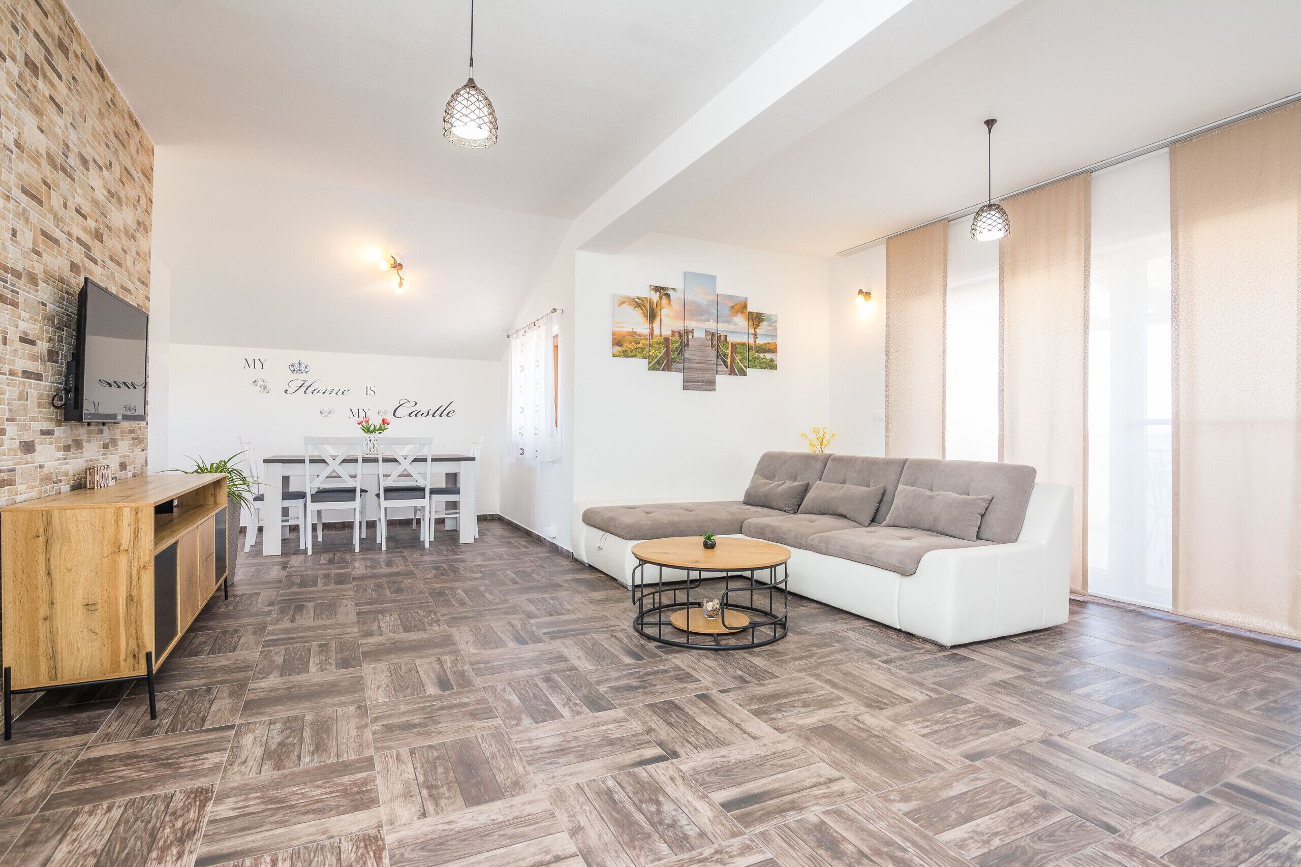 Uma sala de estar moderna com um sofá, mesa de centro e área de jantar com mesa e cadeiras brancas.