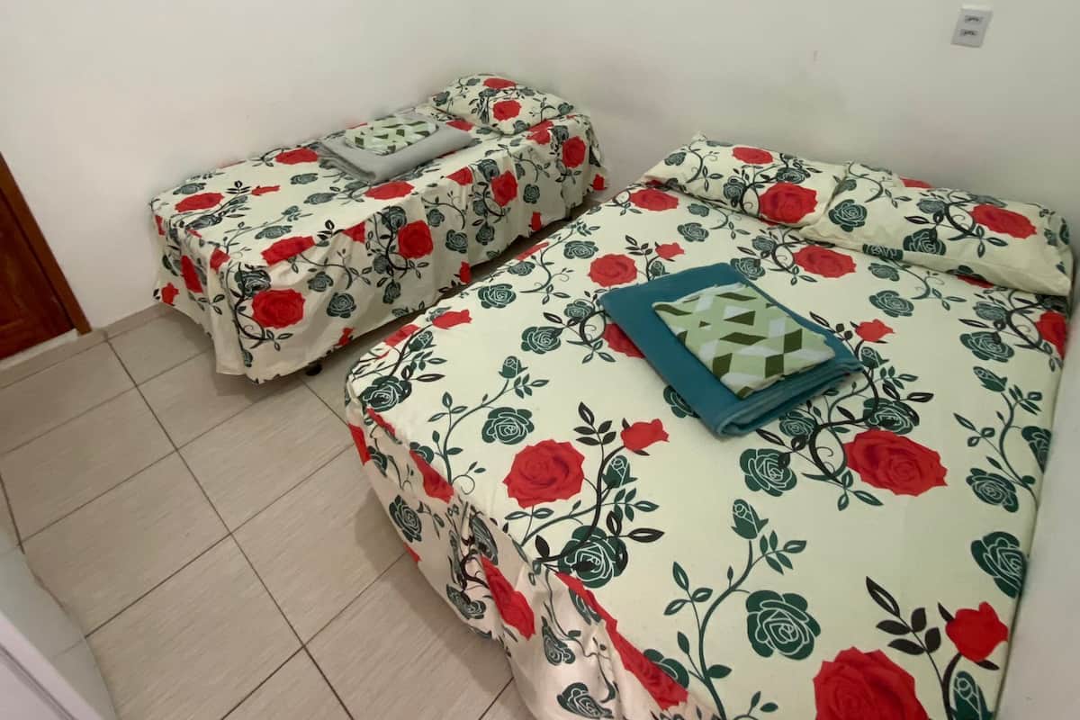 Quarto com duas camas, cada uma com roupa de cama florida.