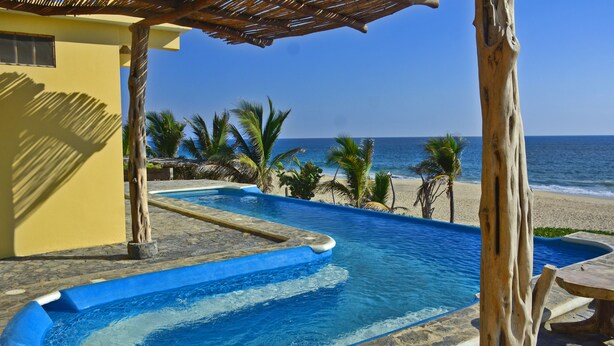 Uma área de piscina com vista para a praia e o oceano.