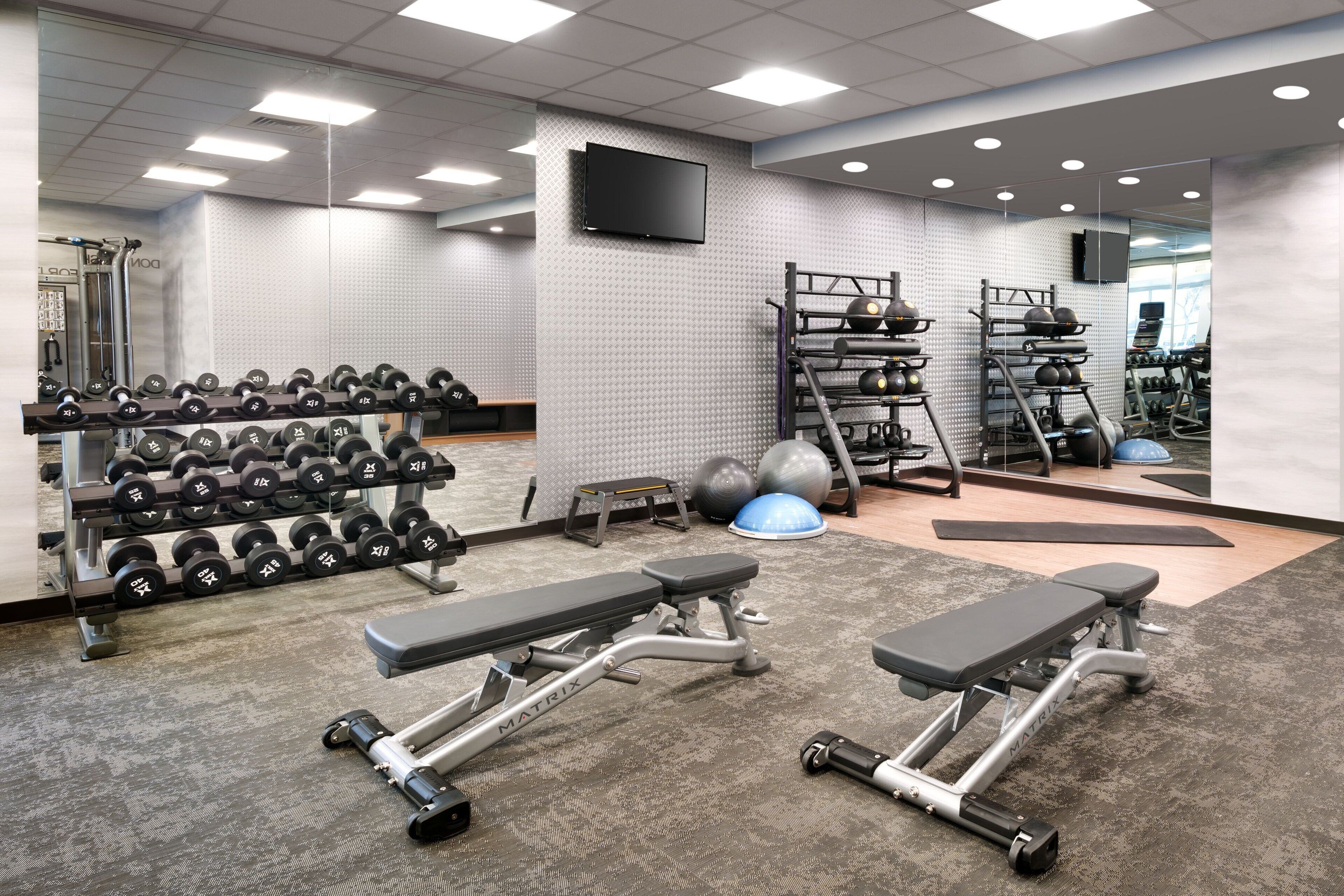Uma academia com equipamentos de musculação, esteiras e bolas de exercício.