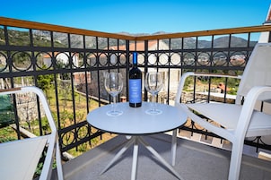 Uma varanda com uma mesa e duas cadeiras, uma garrafa de vinho e dois copos de vinho.