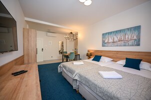 Quarto de hotel com uma cama grande, uma escrivaninha, uma cadeira, uma televisão e um quadro na parede.