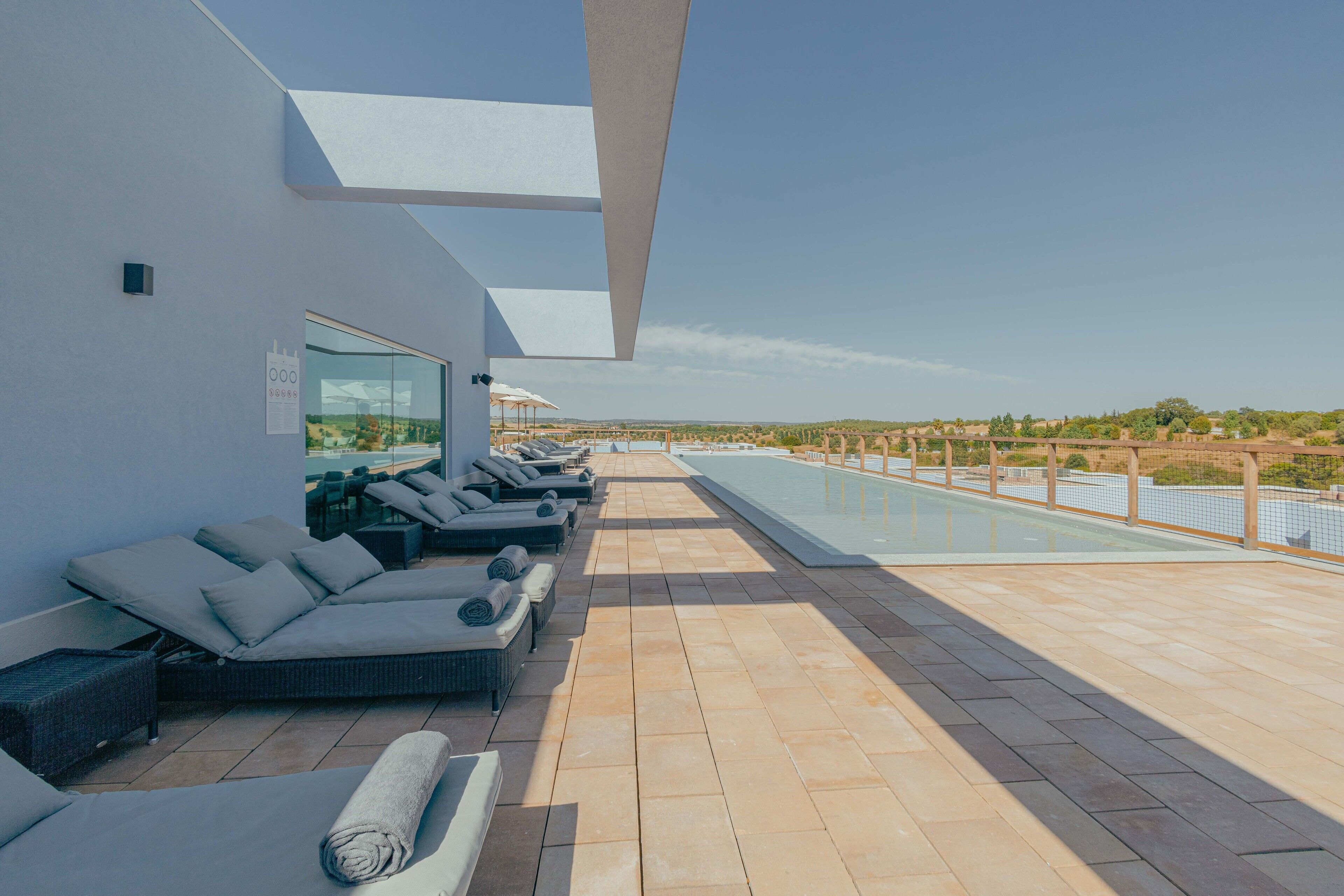 Uma área de estar moderna ao ar livre, com espreguiçadeiras e piscina.