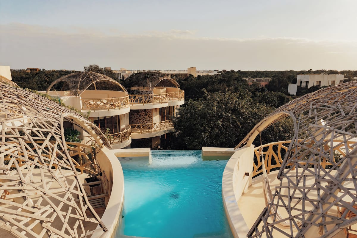 Uma piscina com vista para a área de um resort, incluindo um edifício com varanda e uma estrutura com design em treliça.