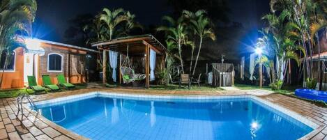 Piscina com borda azulejada, rodeada por um pátio de tijolos.
