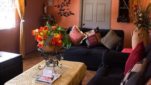 Uma sala de estar acolhedora, com um sofá, uma mesa de centro com revistas e um vaso decorativo com flores.