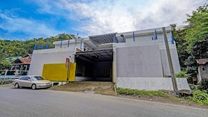 Um edifício com uma entrada ampla, um carro estacionado em frente e uma placa amarela.