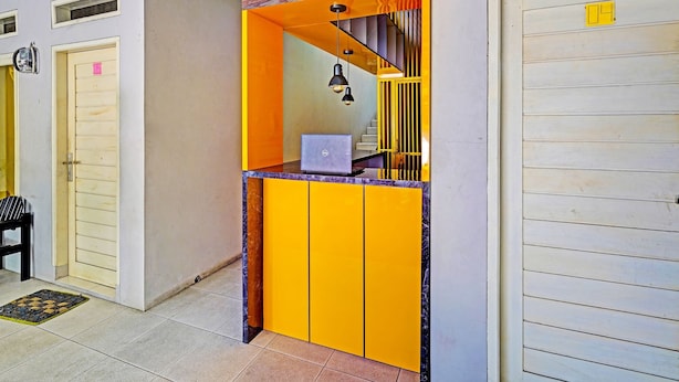 Uma área de recepção com balcão, mesa e escada com corrimão amarelo.