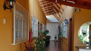 Um corredor com piso de azulejos, plantas em vasos e um extintor de incêndio.