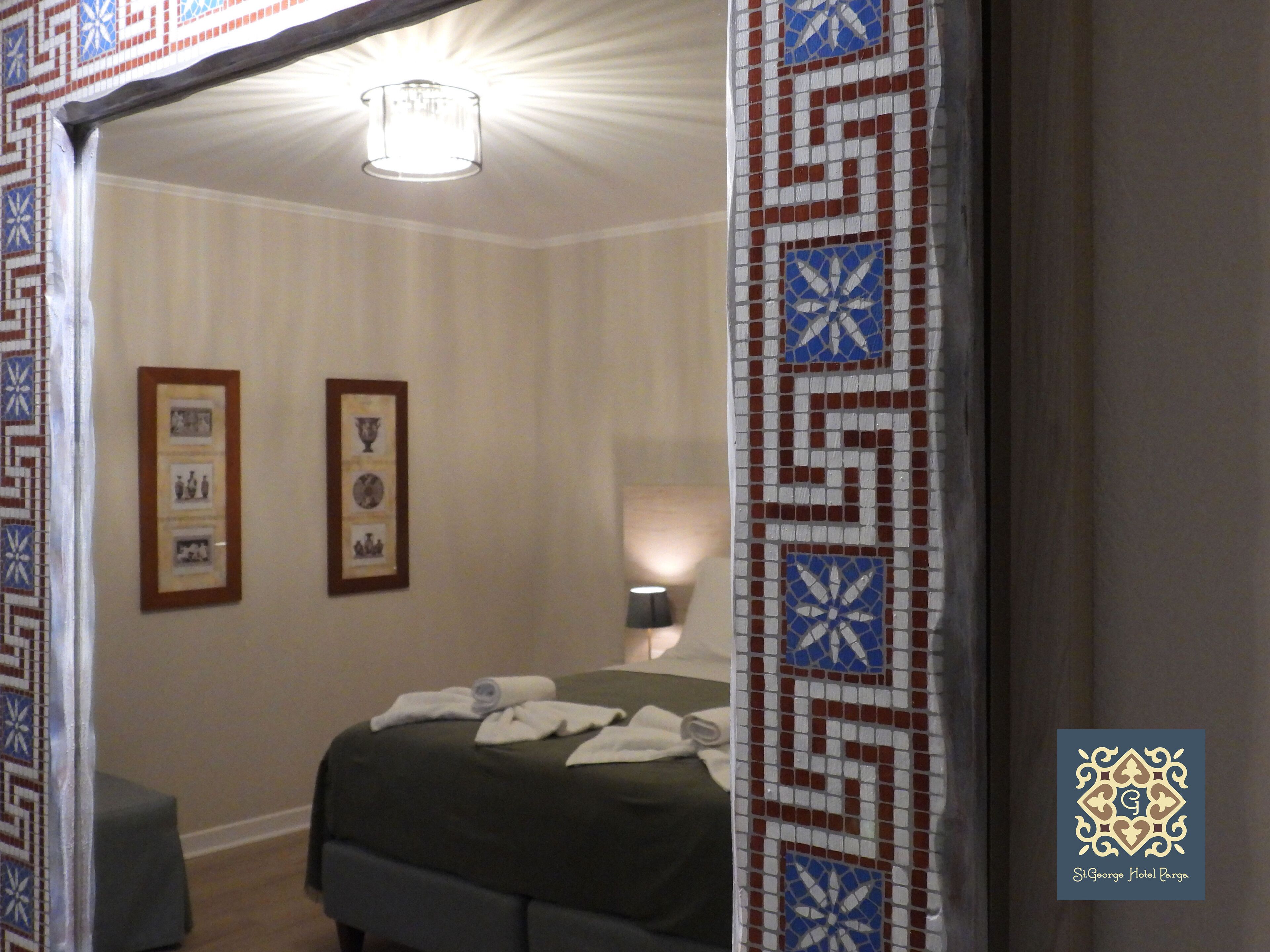 Quarto de hotel com cama, luminária fixada na parede e quadros emoldurados.