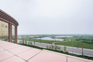 Vista de um terraço de edifício com vista para uma estrada, um rio e vegetação.