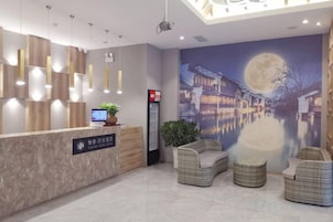Uma área de recepção de hotel com design moderno, balcão de atendimento, espaço de espera e um grande mural na parede.