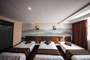 Quarto de hotel com três camas, um grande mural na parede e duas luminárias fixadas na parede.
