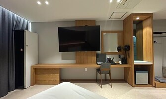 Quarto moderno com cama, escrivaninha, cadeira, televisão e guarda-roupa.