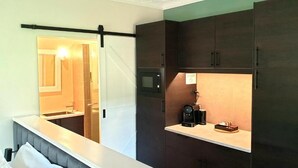 Cozinha compacta com micro-ondas, cafeteira e um pequeno armário.