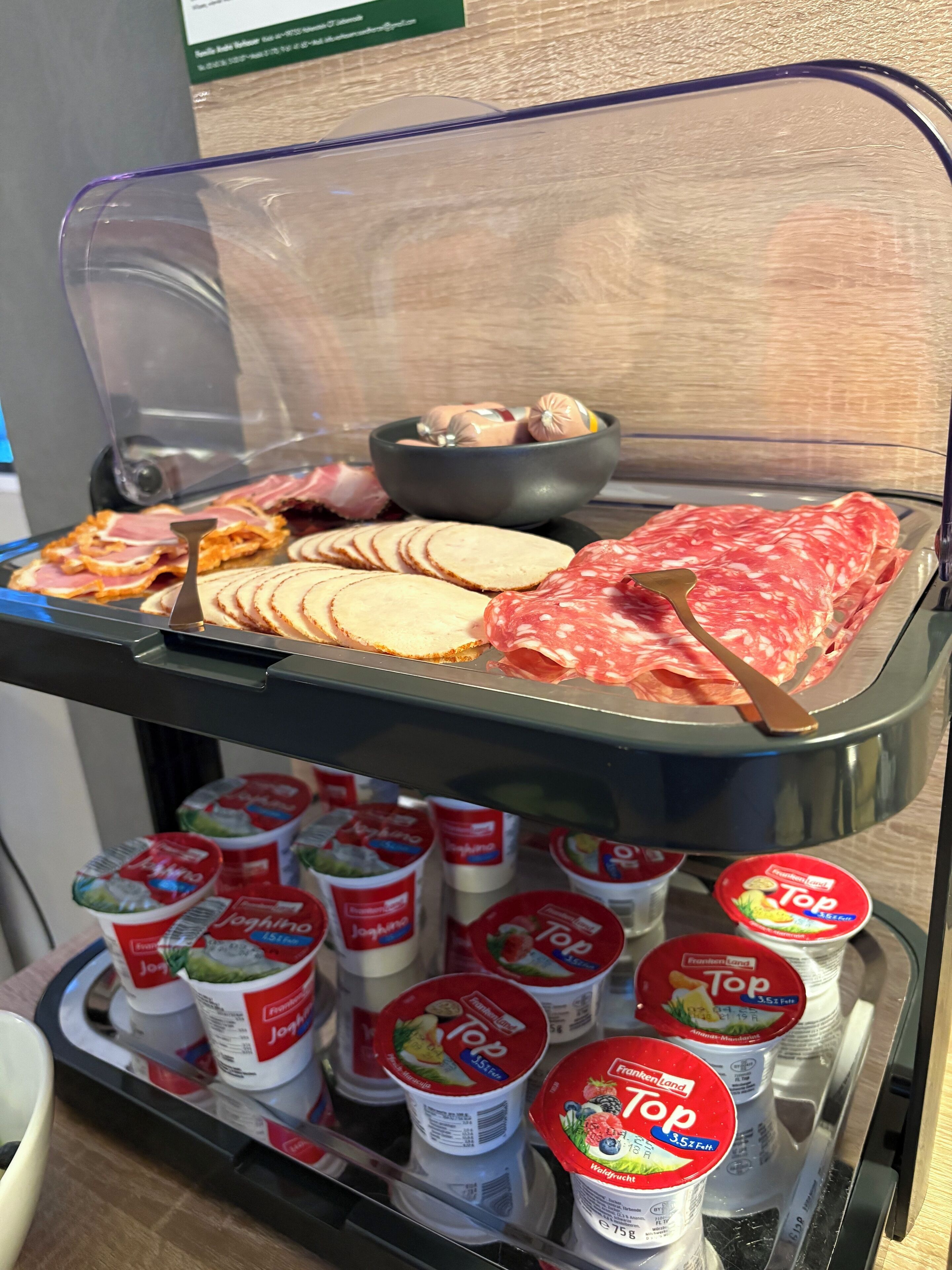 Exposição de alimentos com fatias de carne, queijo e recipientes de iogurte.