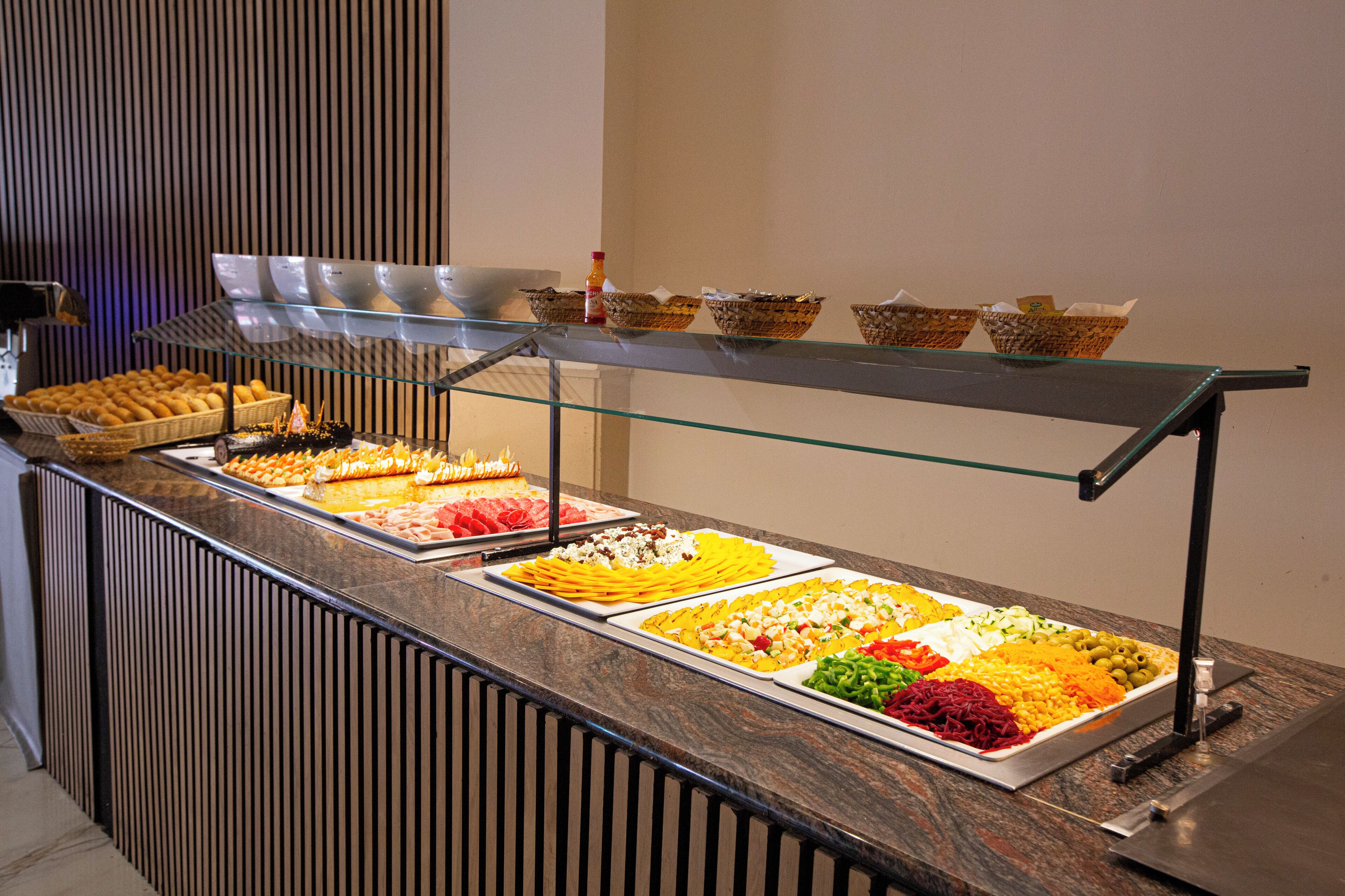 Buffet com diversos alimentos e cestas sobre um balcão.