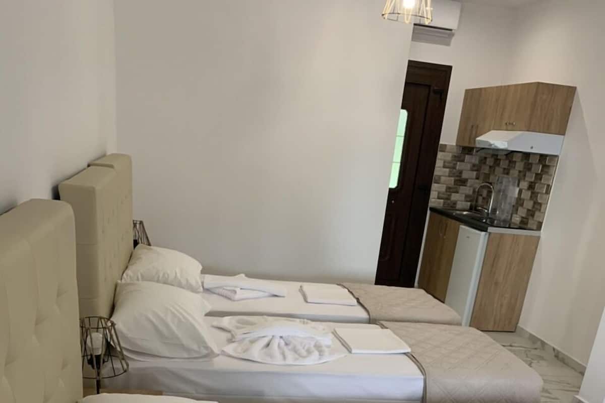 Quarto de hotel com duas camas, cada uma com toalhas e roupões brancos dobrados com cuidado.