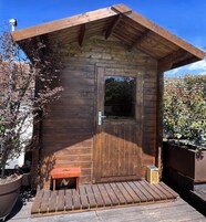 Uma cabana de madeira com porta, um pequeno banco e um deck de madeira.