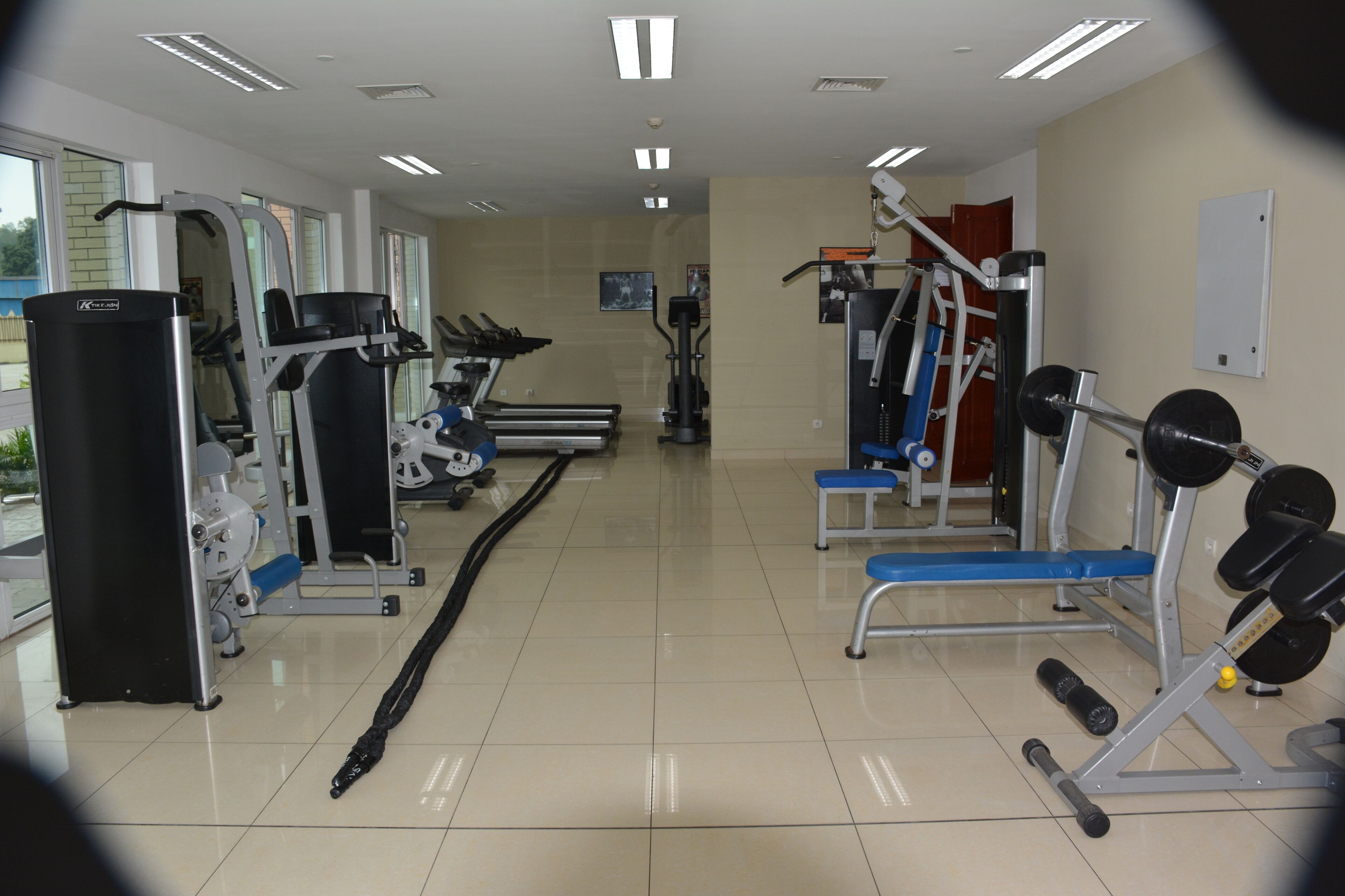 Uma academia com diversos aparelhos de exercício, um banco e pesos.