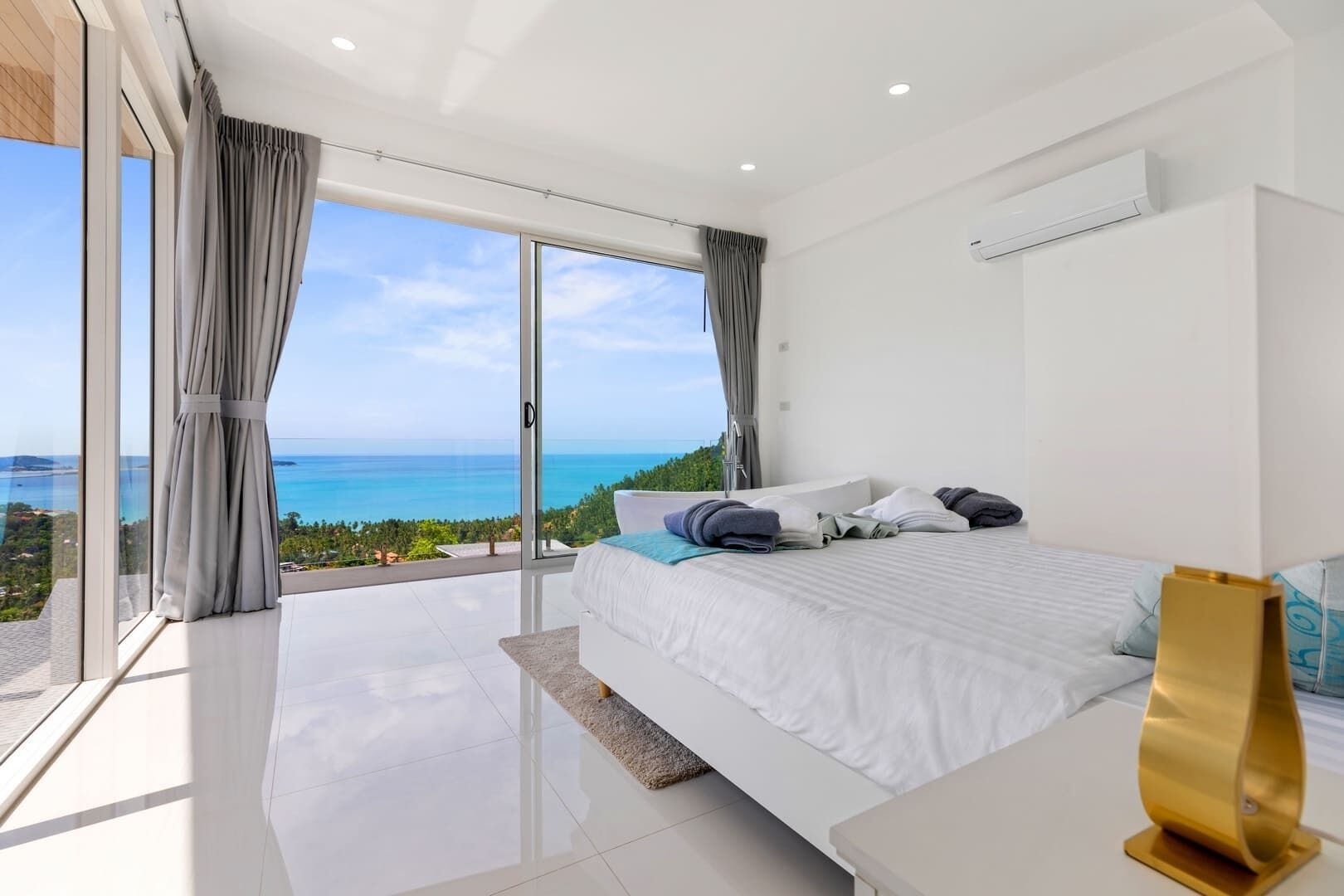 Quarto moderno com uma cama grande, vista para o oceano e varanda.