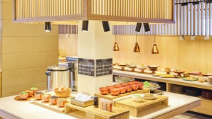 Uma mesa de buffet com diversos alimentos, um espaço para café e um quadro de cardápio.