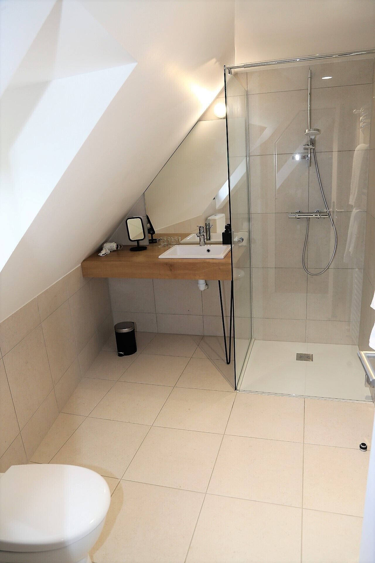 Um banheiro moderno com box de vidro, toucador de madeira e vaso sanitário branco.