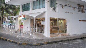 Um edifício moderno e branco com vários andares, unidades de ar condicionado e uma entrada visível com portas de vidro.