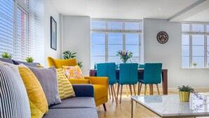 Uma sala de estar moderna com sofá, poltronas verde-água e uma mesa de jantar.