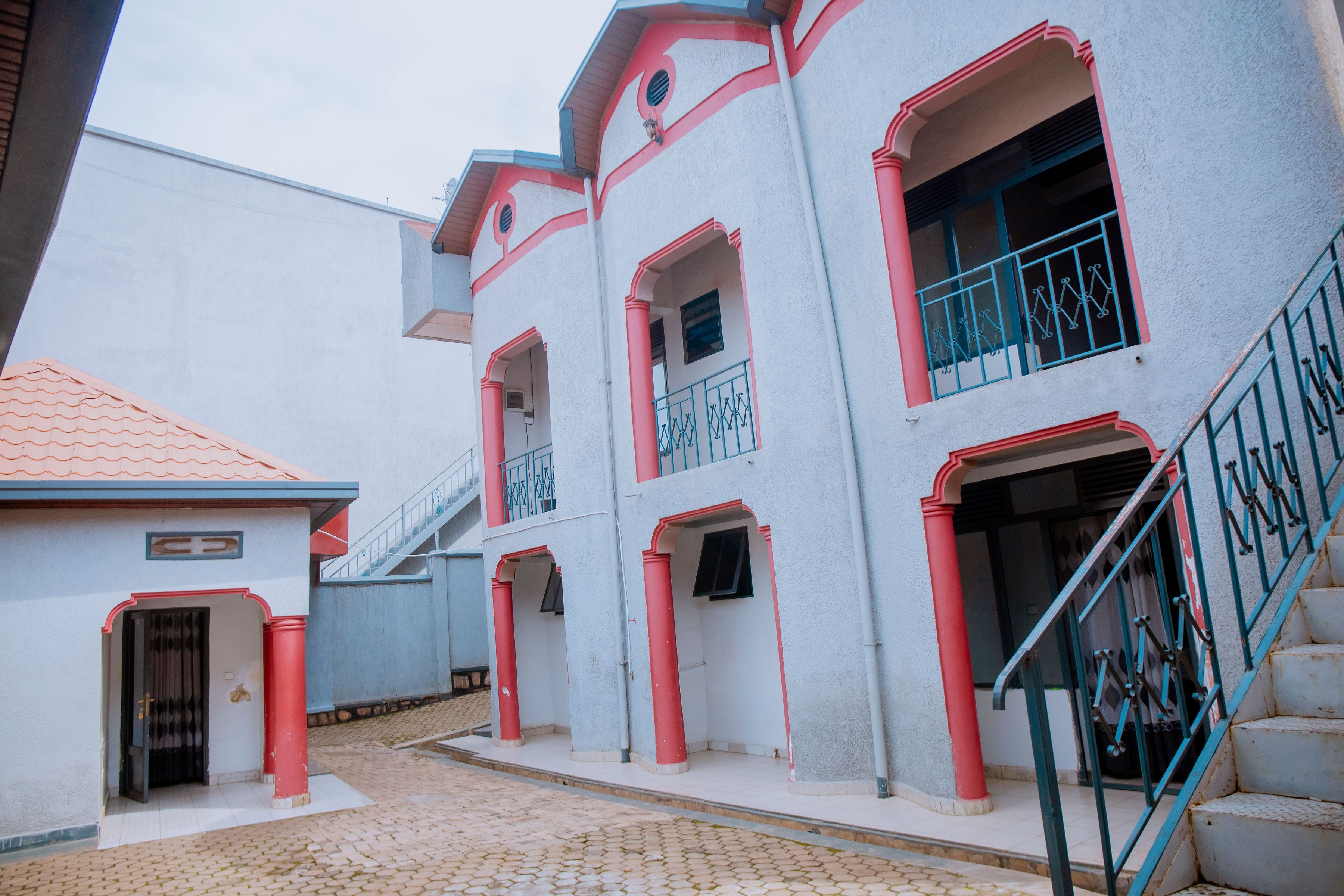 Um edifício com fachada vermelha e branca, uma escadaria e chão de paralelepípedos.