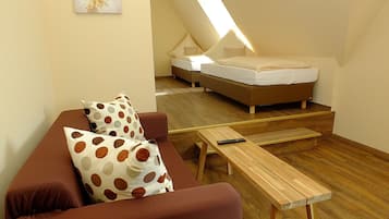 Quarto moderno e compacto com sofá marrom, mesa de centro de madeira e cama ao fundo.