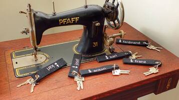 Máquina de costura Pfaff antiga, com chaves identificadas por nomes, sobre uma mesa de madeira.