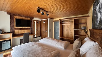 Quarto com decoração em madeira, incluindo uma cama, escrivaninha, cadeira, televisão e guarda-roupa.