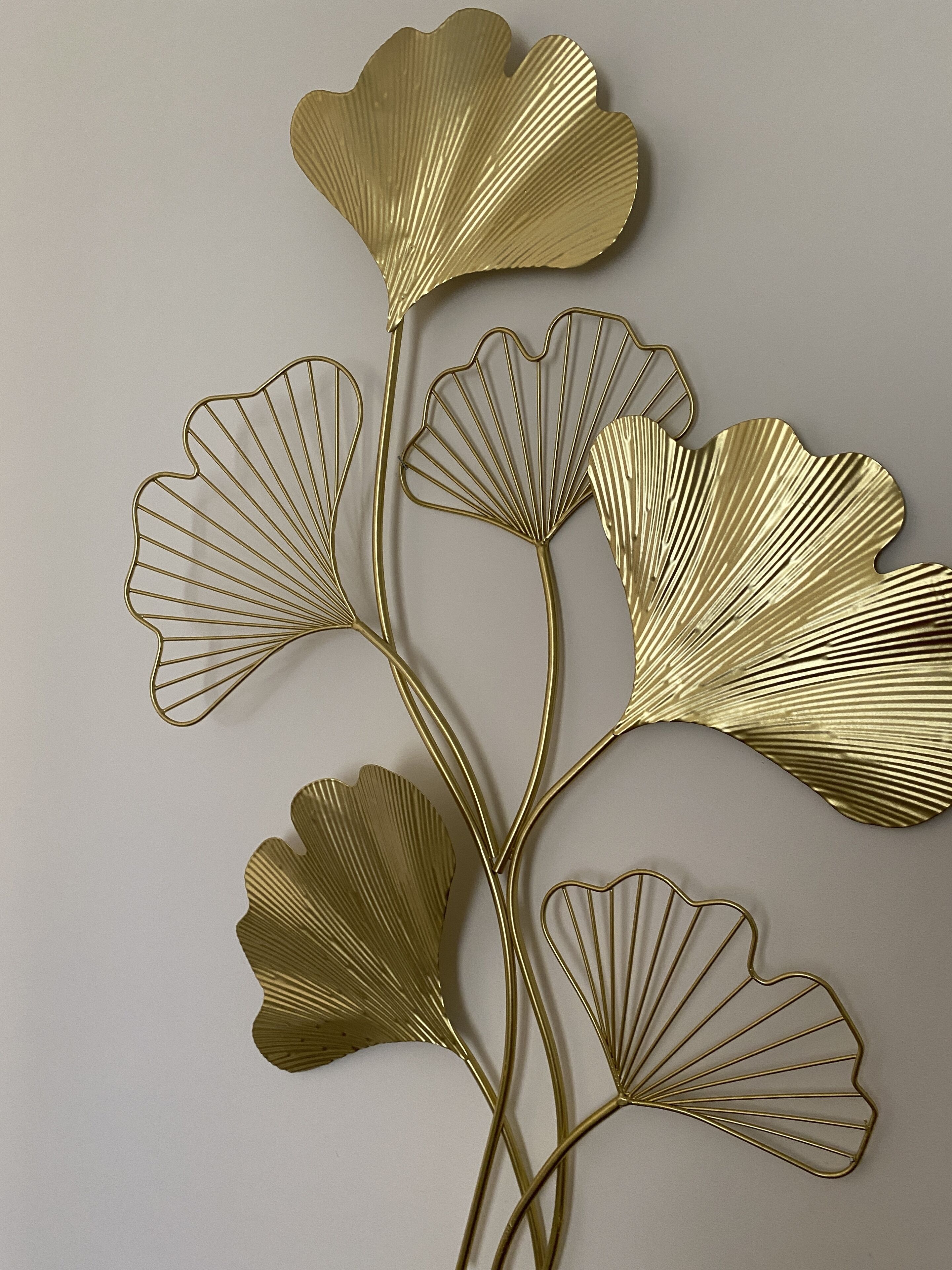 Uma peça decorativa na parede, com design que lembra folhas de metal.