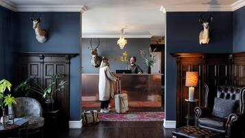Um saguão de hotel com balcão de recepção, um lustre e decorações de parede com chifres de animais.