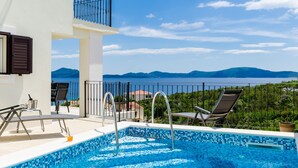 Uma área de piscina com vista para o mar e montanhas.