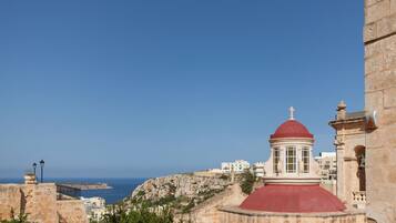 Um edifício costeiro com cúpula vermelha e paredes de pedra, com vista para o mar.