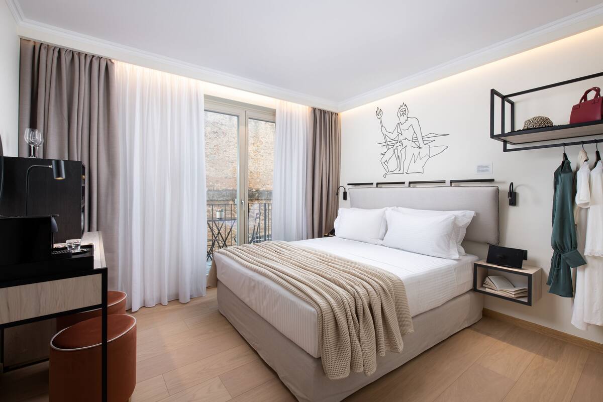 Quarto de hotel moderno com uma cama grande, uma escrivaninha, uma cadeira e um guarda-roupa.