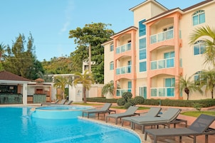 Um hotel com piscina, espreguiçadeiras e um bar.