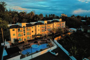 Um hotel com várias varandas, piscina e vista para o mar.